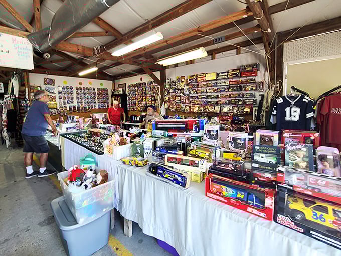 A collector's paradise at Hudson's Surfside Flea Market! Sports memorabilia, model cars, and treasures galore fill this vendor's booth where shoppers browse under rustic wooden beams.