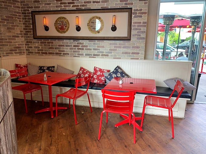Nautical meets cozy at Lobster West's interior, where porthole mirrors and brick walls create a maritime vibe. Those red chairs aren't just stylish—they're a beacon for seafood lovers.