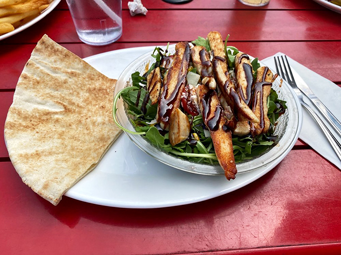 For those seeking lighter fare, this arugula salad with grilled chicken offers a momentary reprieve from burger indulgence—though you'll be eyeing your neighbor's plate.