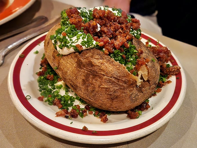 Not just any baked potato—this loaded beauty comes dressed for dinner with all the fixings, ready for its supporting role in the meat symphony.