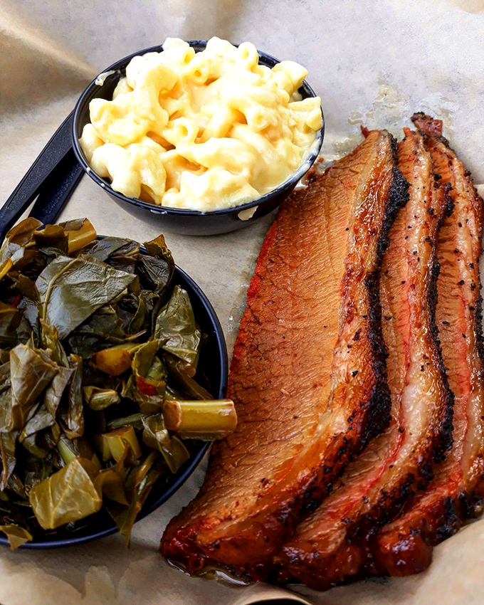 Brisket with that telltale pink smoke ring, collard greens, and mac and cheese—the holy trinity of Southern-inspired comfort on a single tray.