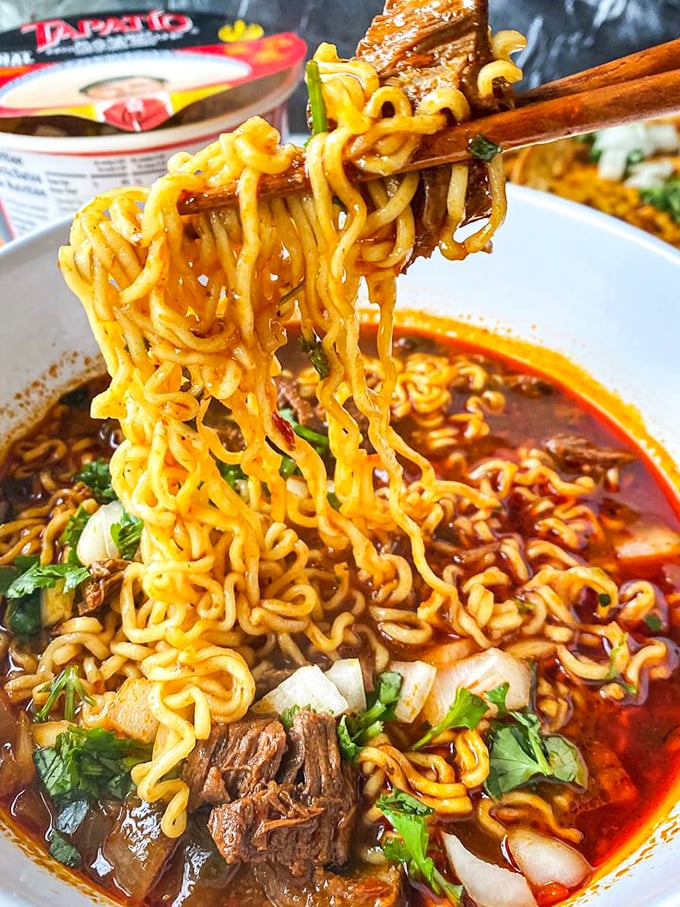 These noodles aren't just swimming in broth—they're performing synchronized flavor dives with tender beef in a spicy pool that demands your full attention.