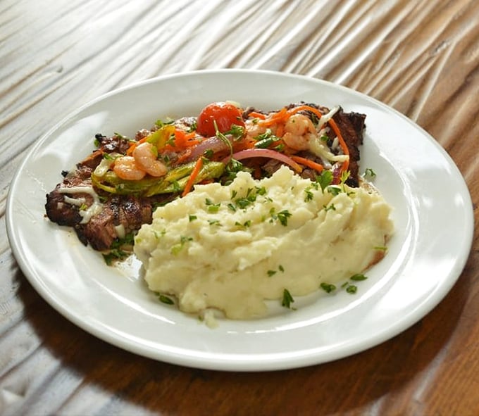 The Bistek Especial brings the drama—tender steak sharing the spotlight with colorful vegetables and mashed potatoes that deserve their own standing ovation.