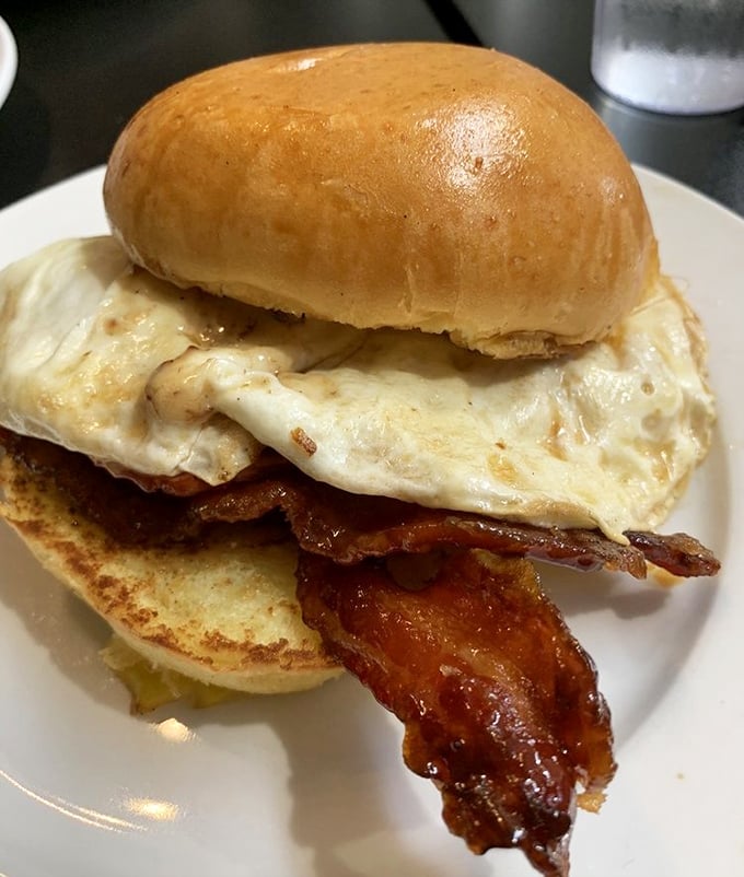 Breakfast architecture at its finest: crispy bacon and a perfect egg on a brioche bun—proof that mornings can indeed be something to celebrate.