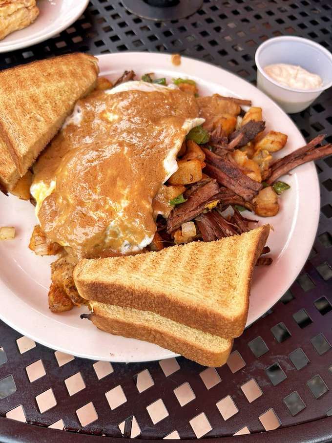 The brisket hash doesn't just sit on the plate—it commands attention. Those eggs and that sauce are having the breakfast romance we all deserve.