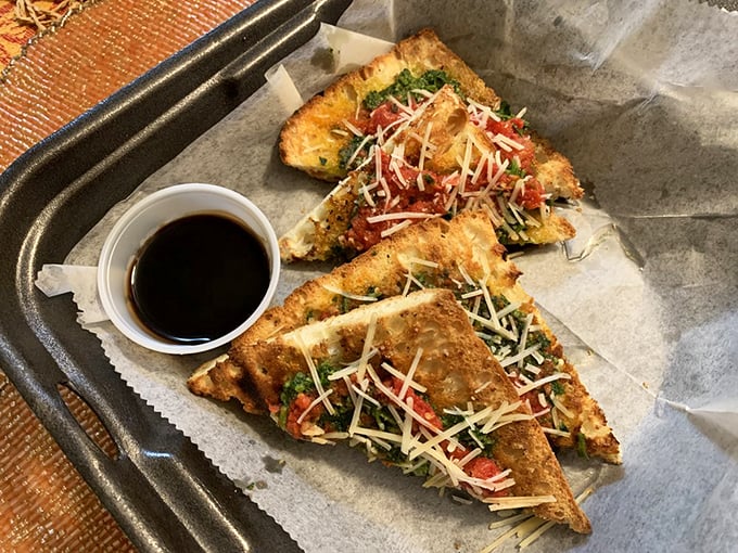 Bruschetta triangles that crunch like autumn leaves, topped with a confetti of fresh ingredients and a shower of cheese—simple perfection on parchment.