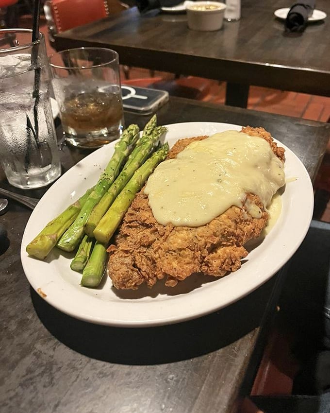 Chicken fried steak wearing its cream gravy like a royal robe, with asparagus standing at attention alongside—comfort food elevated to art form.