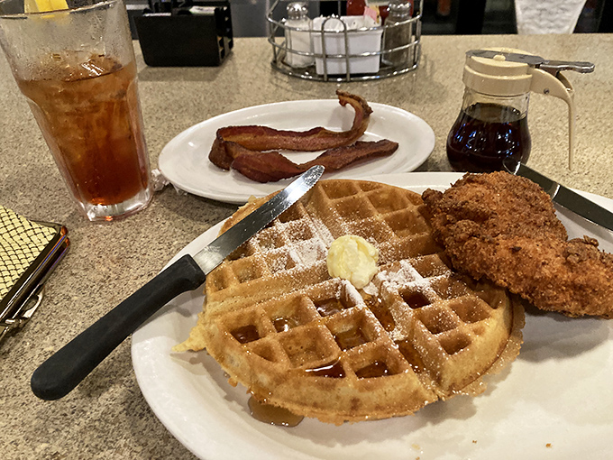 The breakfast power couple that never disappoints—golden waffles with a crispy fried chicken companion, plus bacon because why stop there?
