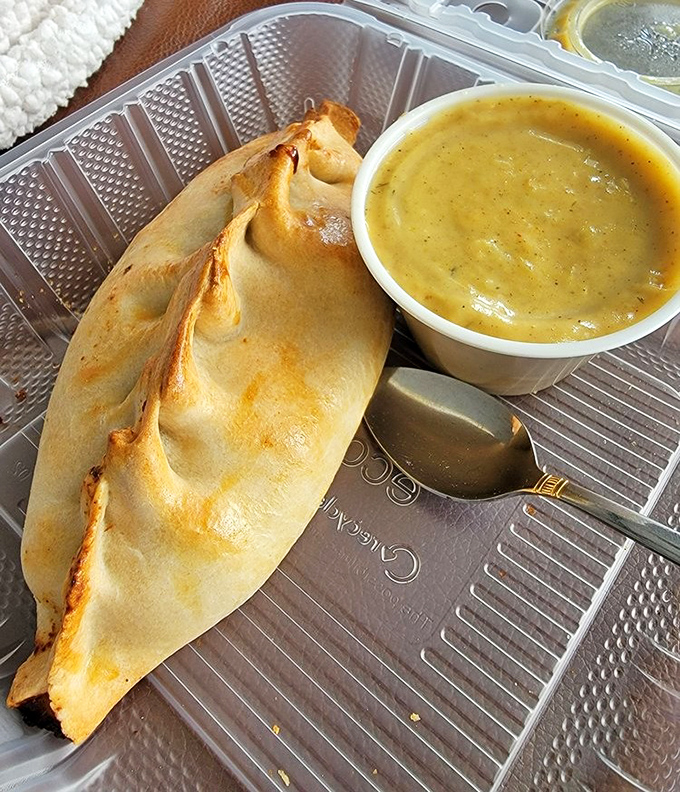This isn't just a pasty—it's a portable feast of savory filling wrapped in flaky pastry with curry sauce standing by for dunking duty.