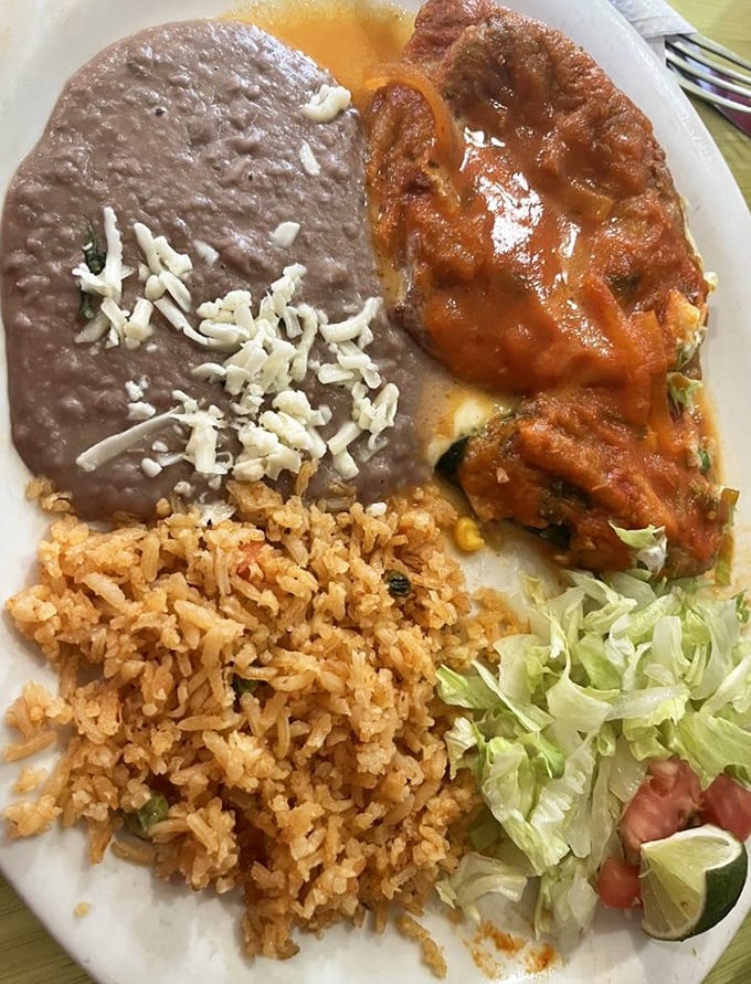 The chile relleno doesn't just share the plate – it commands it. That red sauce blanket tucked around the stuffed pepper is comfort food defined.