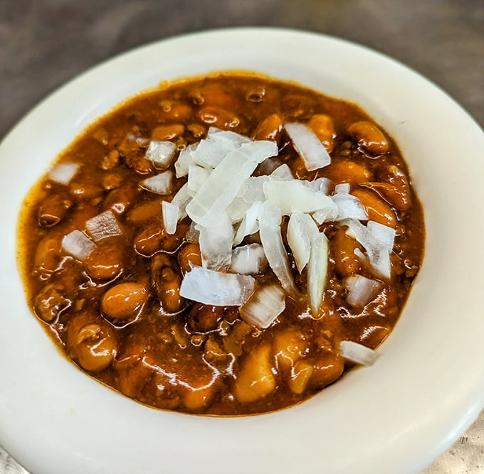 A bowl of their famous chile with beans, topped with diced onions—proof that sometimes the most unassuming dishes carry the most profound flavors.