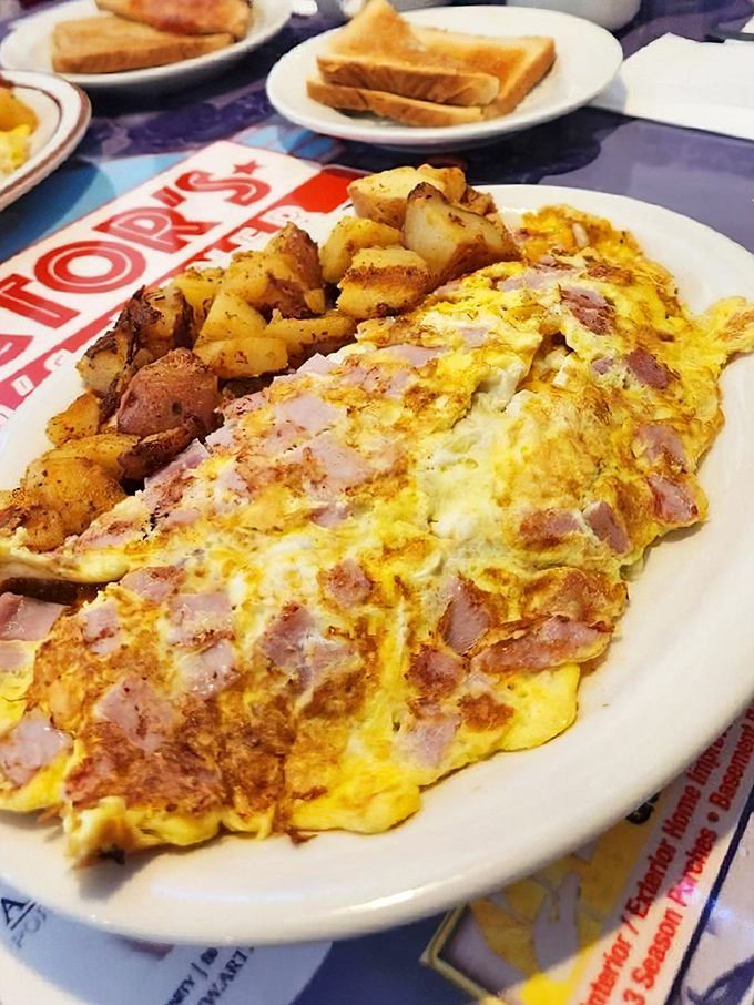An omelette so stuffed with ham it's practically wearing a pork tuxedo. Those home fries on the side aren't just a garnish—they're essential supporting actors in this breakfast drama.