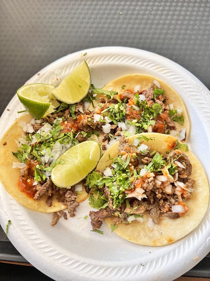 Two perfect tacos with a lime wedge standing by for duty. The cilantro and onion topping isn't garnish – it's an essential supporting actor in this culinary drama.
