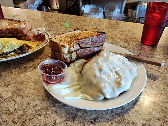 Country fried steak swimming in creamy gravy alongside buttery toast – comfort food that hugs your soul while simultaneously plotting against your arteries.