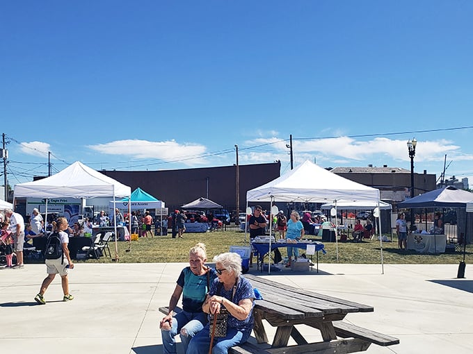 Nothing says "authentic community" like seniors chatting on a bench while farmers market tents billow in the background—small-town America's version of social networking.