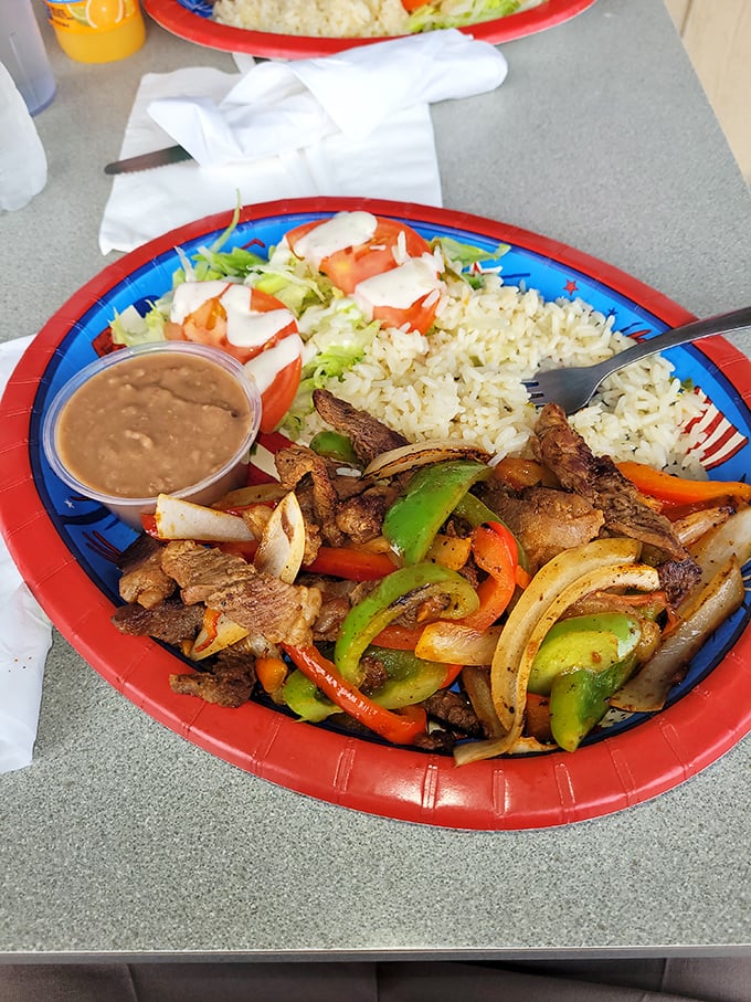 A fajita plate that sizzles with personality—colorful bell peppers and onions dancing with perfectly seasoned meat while rice and beans watch from the sidelines.
