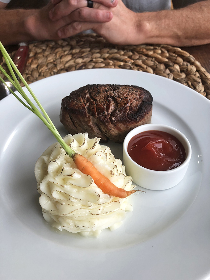 The filet mignon sits proudly next to mashed potatoes sculpted with such precision they deserve their own exhibit at an art gallery.