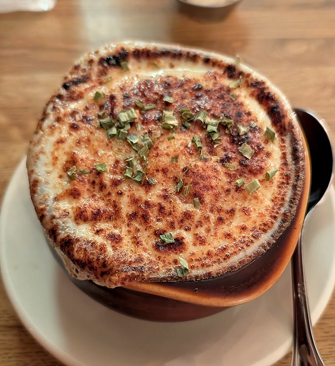 French onion soup with a cheese pull that deserves its own Instagram account. Beneath that golden dome lies a savory treasure worth mining.