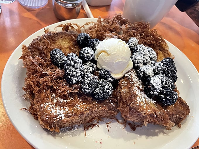 French toast that's gone to finishing school—crispy exterior, custardy interior, and berries that pop like edible jewels.