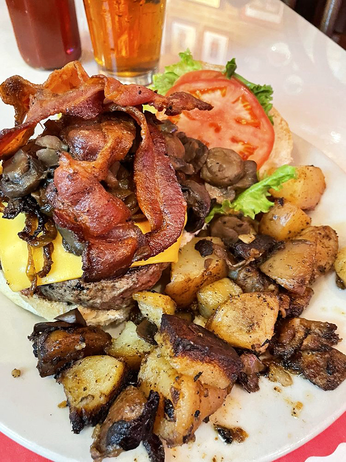 The Kelly Burger arrives like a meaty celebrity, surrounded by bacon, grilled onions and mushrooms—the burger equivalent of having an entourage.