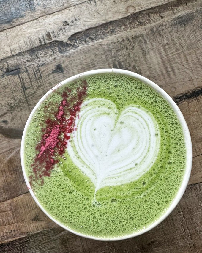 The vibrant green matcha latte, adorned with a heart and pink accent, isn't just a drink—it's a mood-altering experience that energizes without the coffee jitters.
