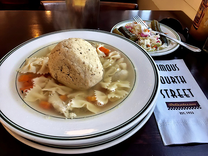 That matzo ball isn't floating—it's holding court in a golden broth that tastes like your grandmother's kitchen, assuming your grandmother was a culinary genius.