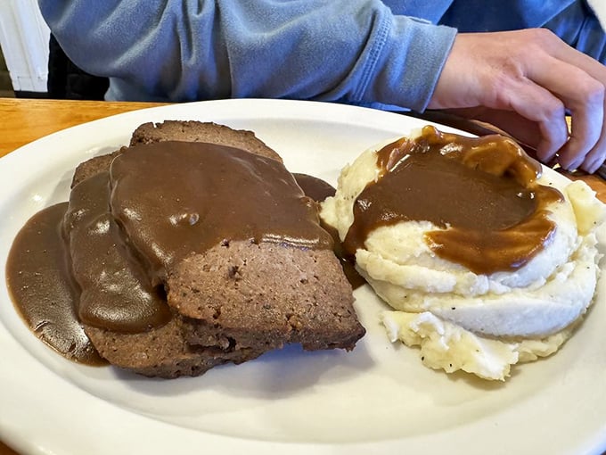 Meatloaf swimming in gravy isn't just comfort food – it's therapy without the hourly rate, served with mashed potatoes as fluffy as childhood memories.