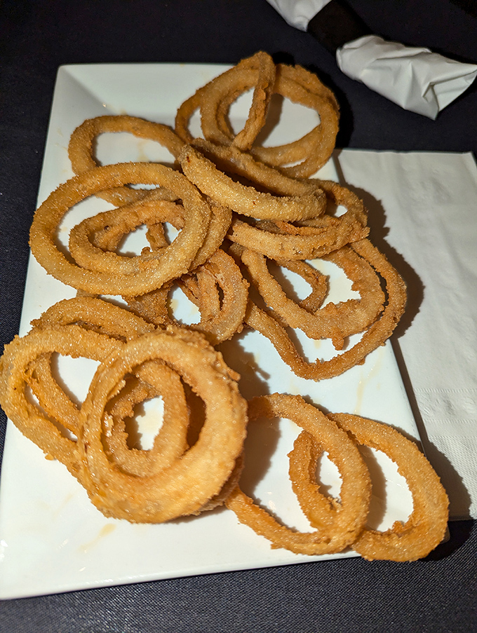 Onion rings stacked like delicious golden halos. Crispy, light, and the perfect companion to whatever else you've ordered—if you're willing to share.