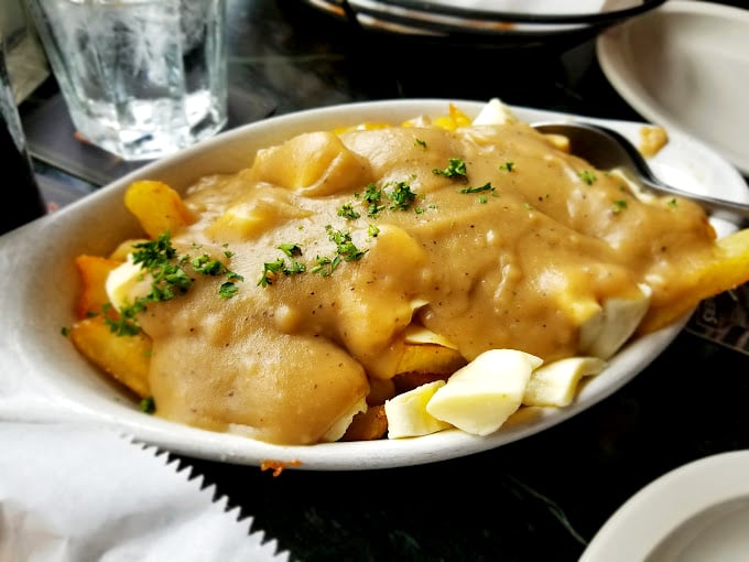 Poutine: where gravy cascades over hand-cut chips and cheese curds like a savory waterfall of pure indulgence.