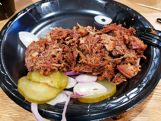 Pulled pork so tender it surrenders without a fight, accompanied by tangy pickles and onions.
