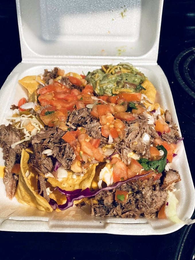 The styrofoam container barely contains the explosion of colors and textures – a portable party of shredded beef and fresh toppings.