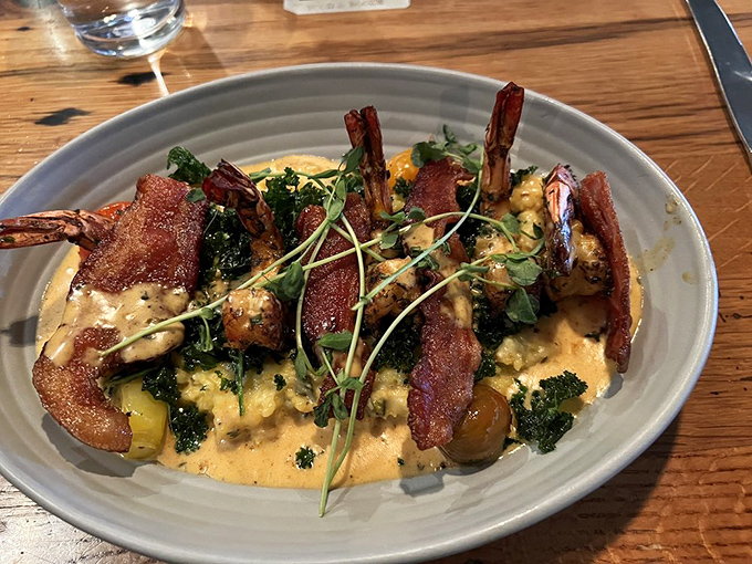 Southern hospitality on a plate. Plump shrimp nestled on creamy grits with crispy bacon standing at attention—a dish worth crossing state lines for.
