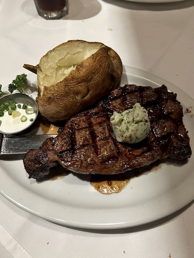 A steak with compound butter melting atop its charred exterior, beside a baked potato that's practically bursting its skin—comfort food elevated.