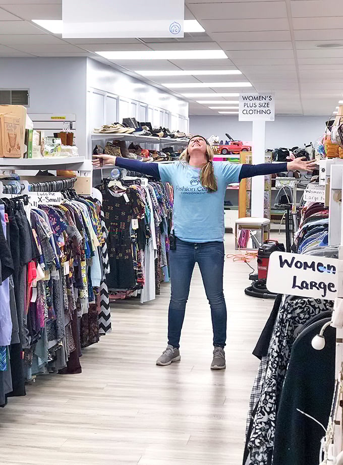The joy of finding fashion gold! This enthusiastic shopper celebrates in the women's section, surrounded by carefully organized racks sorted by size and style.