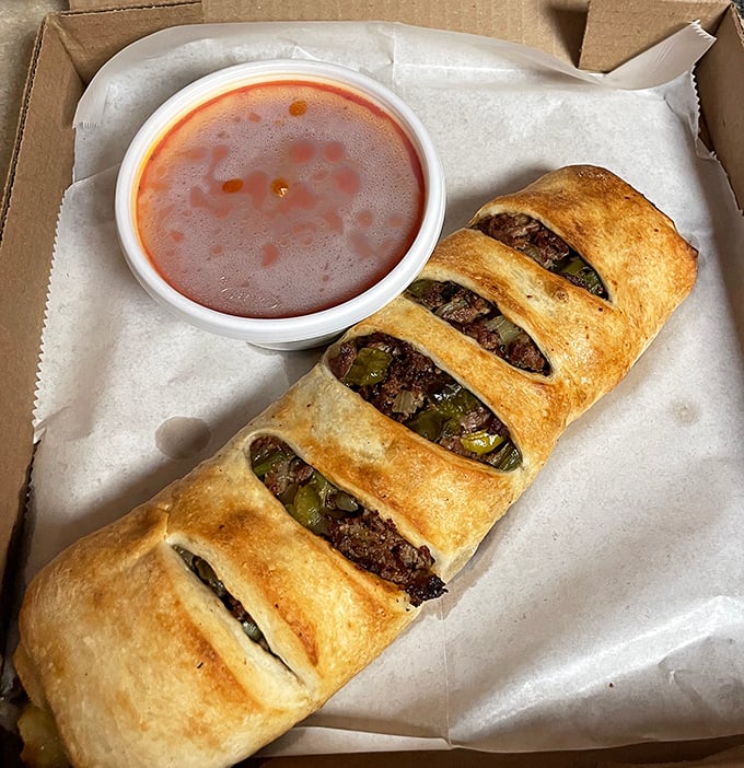 The stromboli—essentially a pizza that decided to roll itself up for your portable eating pleasure. Meat and peppers peek through those perfect slashes.