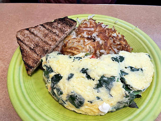 This spinach omelet proves that vegetables can party too, especially when invited to dance with perfectly melted cheese and crispy hash browns.