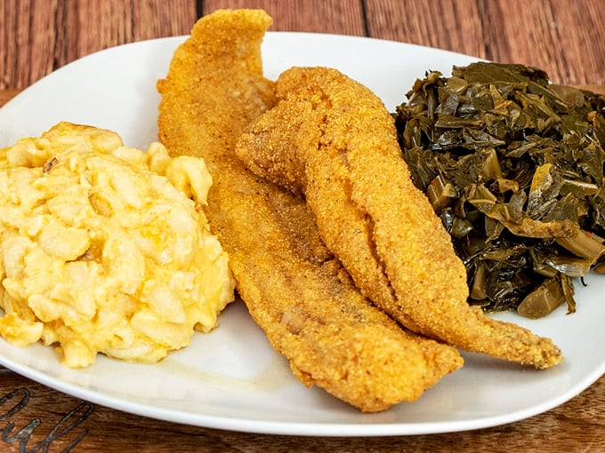 Southern comfort on a plate—crispy catfish flanked by mac and cheese and collard greens. Soul food that speaks directly to your soul.