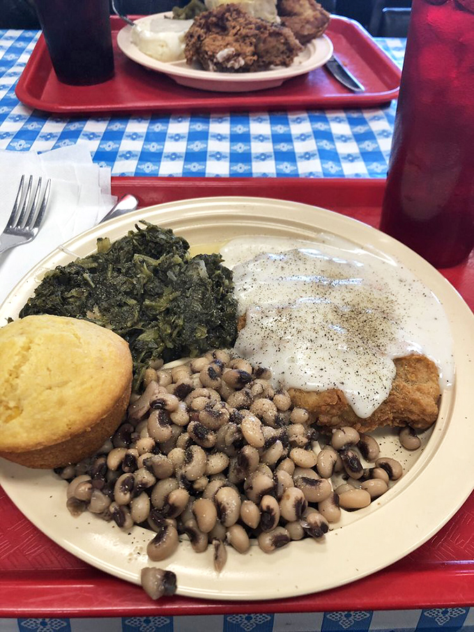 Southern diplomacy on a plate—black-eyed peas and greens making peace with chicken fried steak under a creamy white gravy treaty.