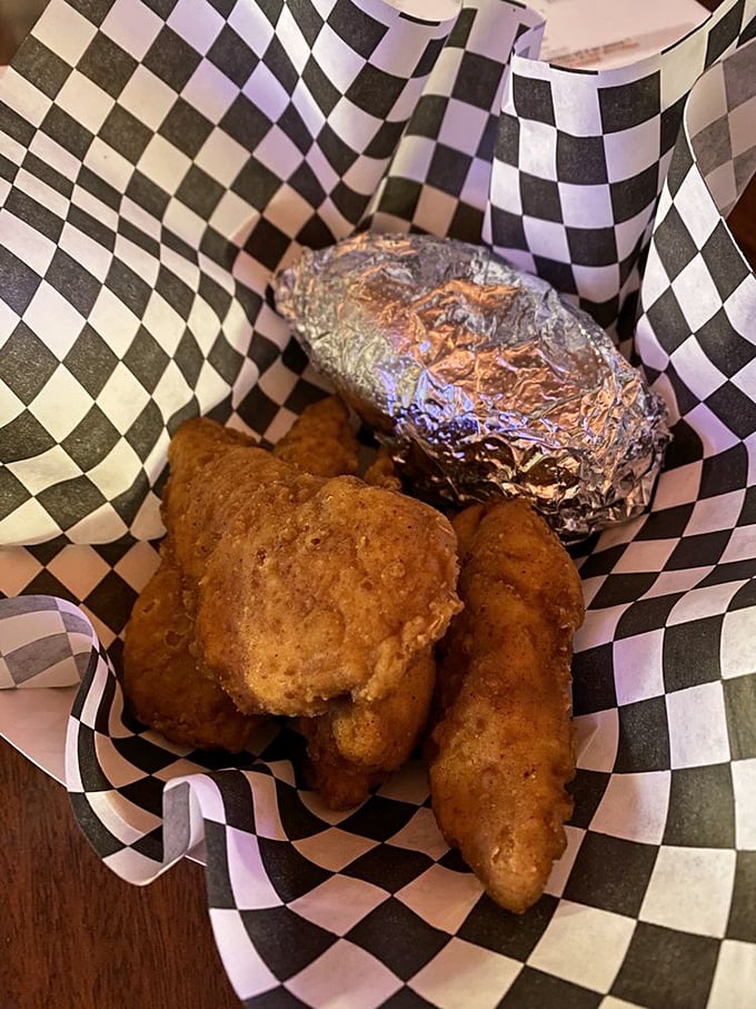 Golden-fried chicken tenders nestled beside a foil-wrapped baked potato – comfort food that speaks the universal language of "everything's gonna be alright."