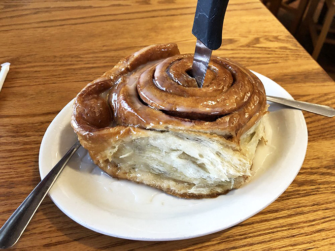 The cinnamon roll that launched a thousand diets—and broke them all. That knife isn't for sharing; it's for savoring every magnificent spiral of cinnamon-sugar bliss.