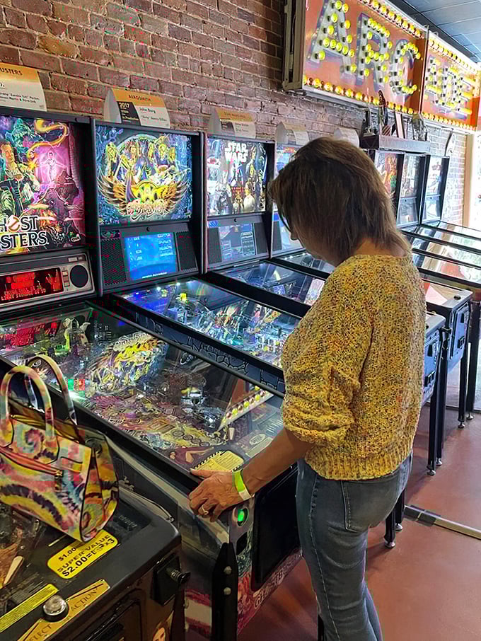 Complete concentration on display as a player in a cozy sweater tackles one of the museum's vintage machines. The stance is universal—slightly hunched, utterly focused.