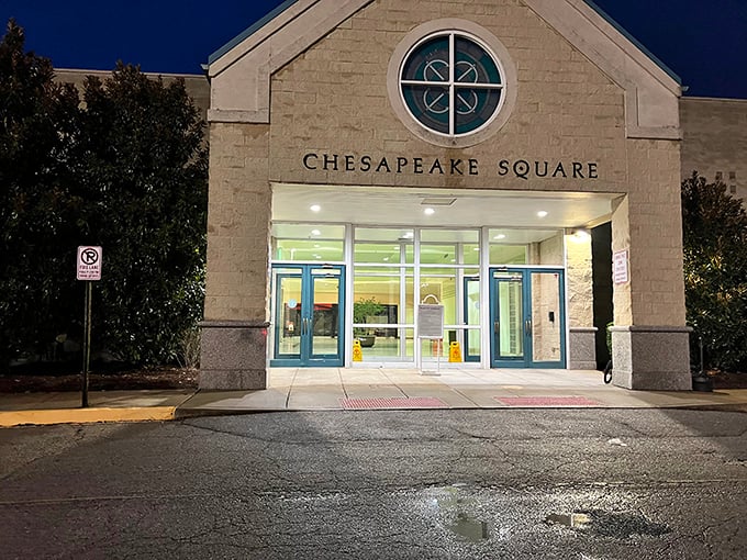 The nighttime entrance to Chesapeake Square glows with welcome. Those glass doors promise climate-controlled bargain hunting regardless of Virginia's weather whims.