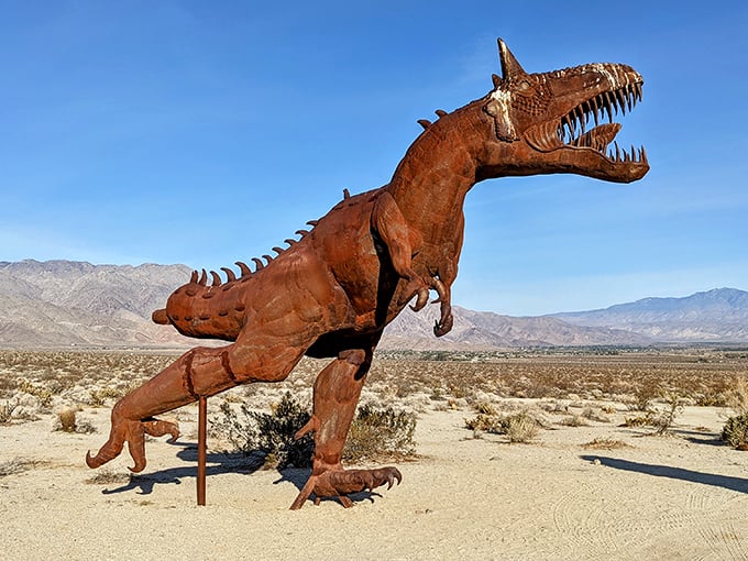 Rust-colored dinosaurs roam the desert landscape, frozen in time but seemingly ready to spring to life at sunset.
