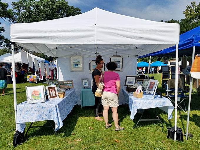 Art lovers gather around framed treasures displayed on grass like an outdoor gallery opening day.