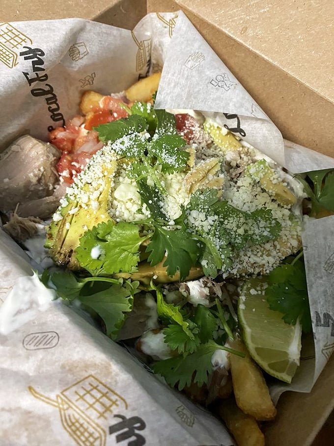 Asada fries with pulled pork—because sometimes one protein isn't enough. This cardboard container holds more flavor than most five-star restaurants.