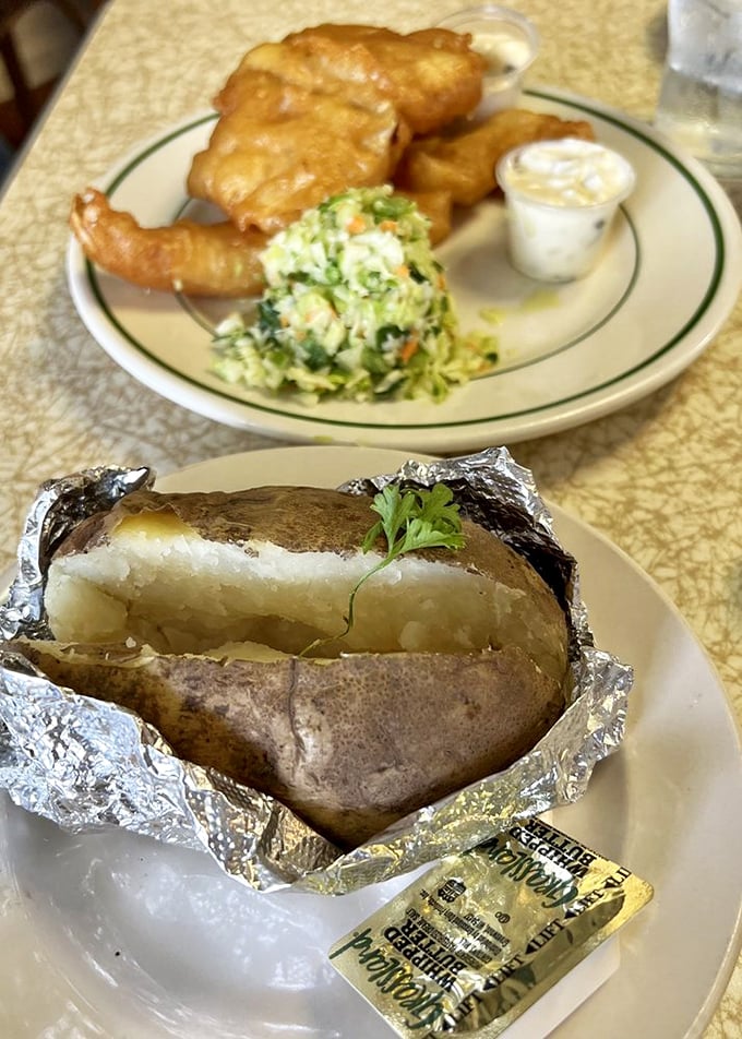 The humble baked potato, wrapped in foil like a precious gift. A starchy sidekick that knows its supporting role in the fish and chips symphony.