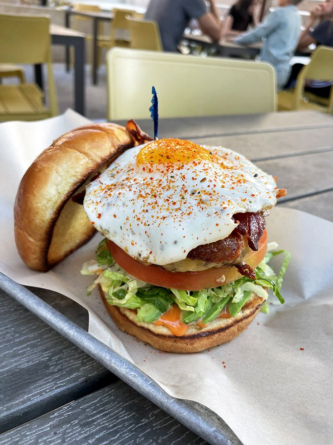 The Battle Royale burger doesn't just sit on the plate—it commands it. That perfectly fried egg is the crown on a monarch of meat.
