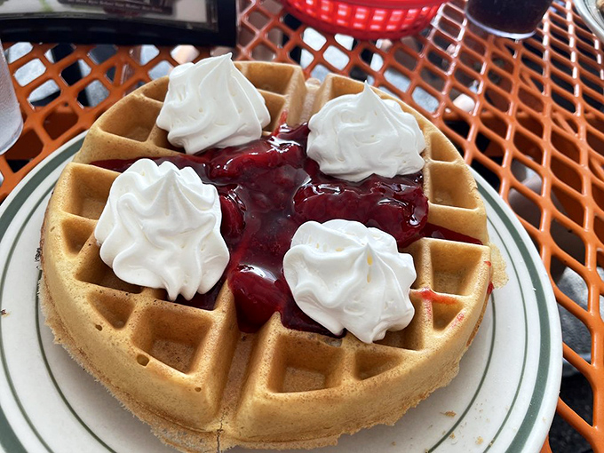 This waffle isn't just breakfast—it's dessert masquerading as a morning meal, complete with whipped cream islands floating in a berry sea.