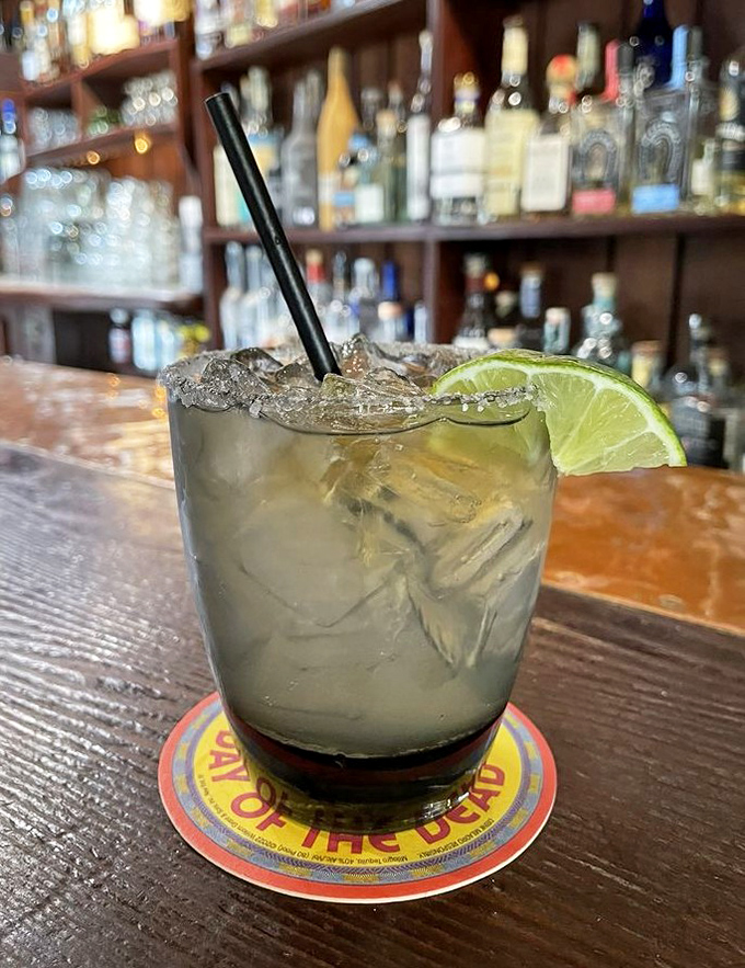 A proper margarita, perched on a wooden bar top—the lime wedge isn't just garnish, it's an invitation to commence the evening's enjoyment.