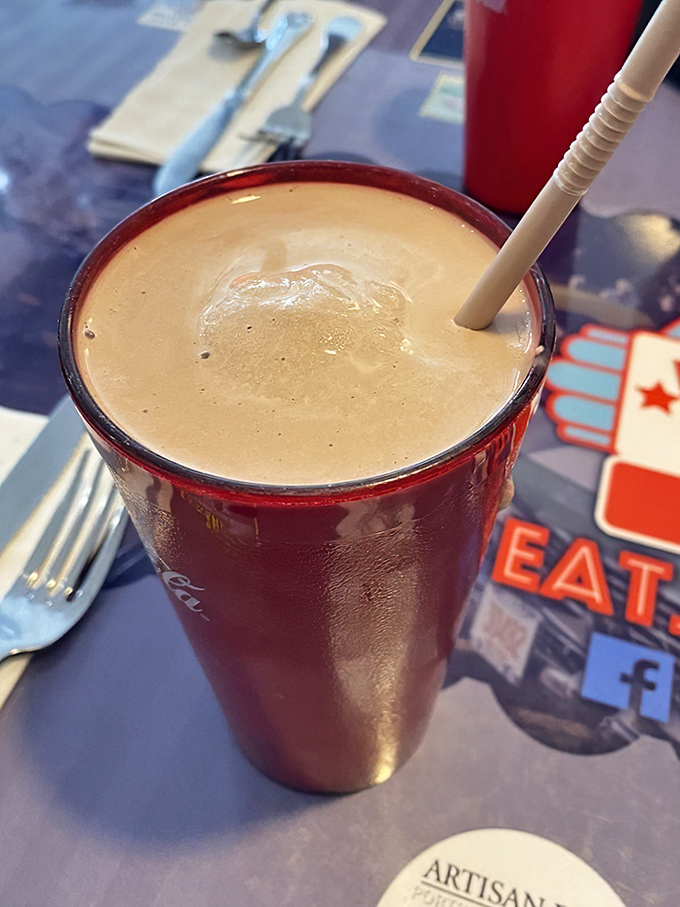 This chocolate frappe isn't just a milkshake—it's a commitment. Served in that classic Coca-Cola glass, it's thick enough to require serious straw technique and zero regrets.